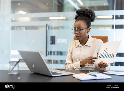 Focused Businesswoman Pointing At Data Chart In Modern Office Setting
