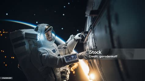 통신 위성의 패널을 서비스하는 전문 우주 엔지니어 용감한 백인 남성 우주 비행사 배경에 행성 지구의 아름 다운면과 함께 우주 공간에서 일하기 개발에 대한 스톡 사진 및 기타