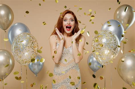 풍선 색종이 근처 이브닝 드레스에 젊은 흥분 재미 멋진 빨간 머리 여성 20 S 는 일반 파스텔 베이지 색 배경 스튜디오에서 고립 된 샴페인과 와인 잔을 개최 생일 파티