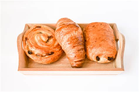 신선한 크로와상 초콜릿 빵과 시 나 몬 달콤한 롤 나무 접시 흰색 배경 전통적인 맛 있는 음식 프랑스 아침 식사와 영양 가득 차 있는 건조 한 포도를 닫습니다 갈색에 대한