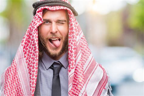 혀를 집어 넣는 절연된 배경 위에 서구인을 입고 긴 머리를 가진 젊은 잘생긴 아라비아 사람 밖으로 재미 있는 표현을 행복 감정 개념입니다 감정에 대한 스톡 사진 및 기타