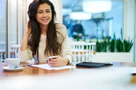 스마트폰 광고에 대 한 흐리게 복사 공간 영역에 앉아 커피 브레이크에 갈색 머리 여자 문자 메시지에 이메일 상자를 확인 하기 위한 카페에서 Wifi 액세스를 사용 하 여