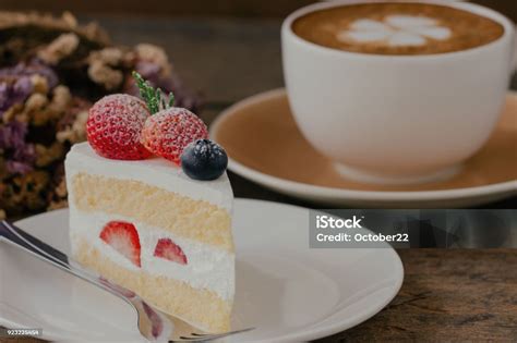 베이커리 숍 이나 카페 레스토랑에서 뜨거운 카푸치노 커피와 함께 만든 맛있고 부드러운 딸기 케 잌 나무 테이블에 제공 됩니다 장식 및 딸기와 휘 핑된 크림 바닐라 스폰지