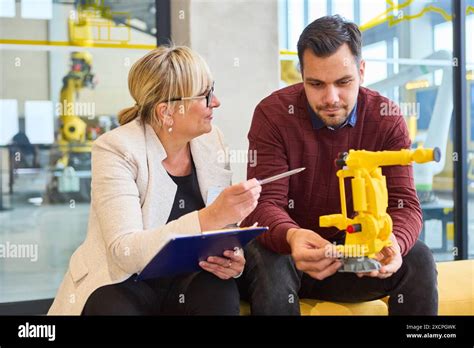 Two Engineers Discussing The Development Of A Robotic Gripper Arm In A