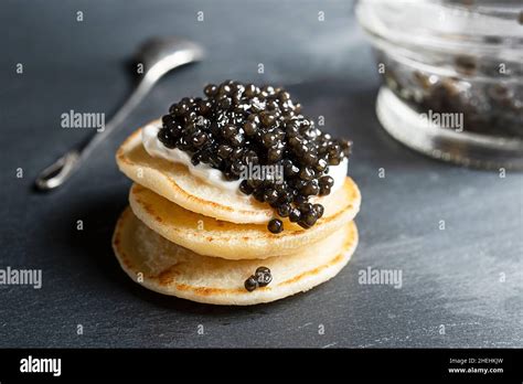 Black Sturgeon Caviar On Small Blini Pancakes A Glass Jar And A Spoon