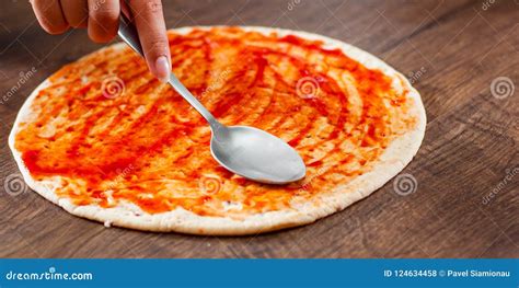 De Kok Van De Handvrouw Met Lepel Smeert Tomatensaus Op Deeg Het Maken Van Italiaanse Pizza Op