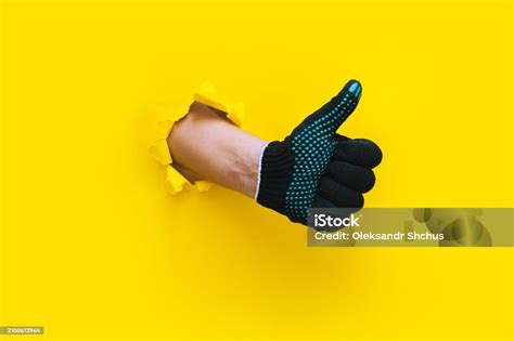 검은색 천으로 된 작업용 장갑을 낀 왼쪽 남자의 손은 엄지손가락을 치켜들고 있다 노란 종이에 작은 찢어진 구멍 좋은 직업 재미