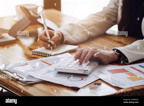 Businss Woman Using Calculator To Calculating A Sales And Profit Accounts On The Report Stock