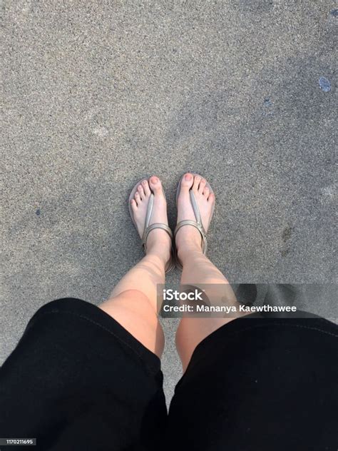 도로 상단보기에 신발발과 다리의 셀카 콘크리트 바닥 배경에 베이지 색 샌들 신발이나 신발을 입고 젊은 여성 거리에 대한 스톡