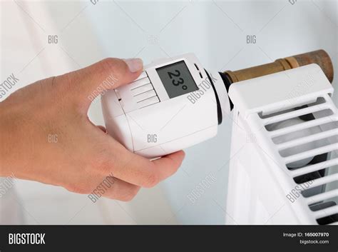 Person S Hand Adjusting Temperature On Thermostat To Control Heat In Central Heating System