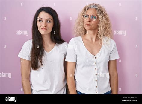 Mother And Daughter Standing Together Over Pink Background Smiling