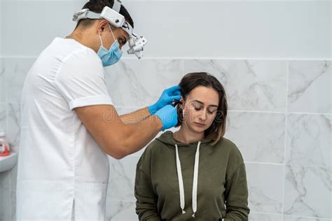 Handsome Male Ent In A Mask With A Lamp Makes An Examination Of A Girl