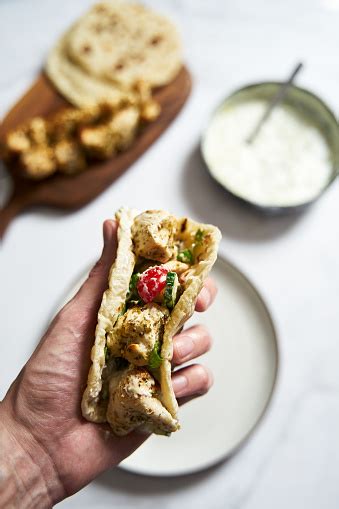 그리스 치킨 수블라키 오나 피타와 신선한 야채와 짜찌키 소스 치킨 수블라키와 함께 피타 하나를 들고 있는 손 배경에는 닭고기와