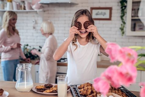 그녀의 눈 근처에 초콜릿 쿠키를 들고 아름다운 어린 소녀 딸 어머니와 할머니는 부엌에서 요리 여성 세대는 함께 베이킹 가정 생활에 대한 스톡 사진 및 기타 이미지 Istock