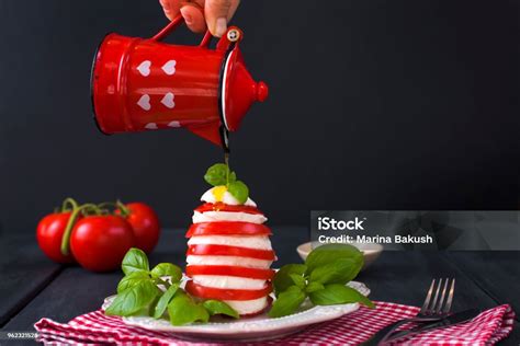 전통적인 이탈리아 Caprese 샐러드어두운 배경에 토마토 모 짜 렐 라 치즈와 바 질 슬라이스 닫습니다 여성 손 기름 부 어 건강한 생활방식에 대한 스톡 사진 및 기타