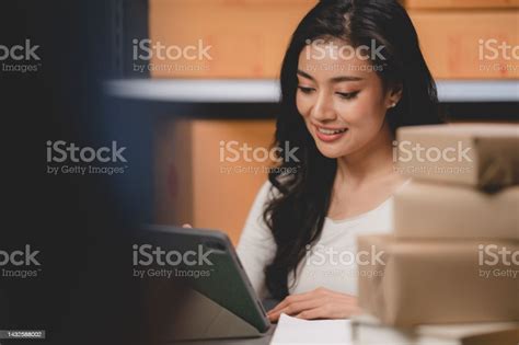 온라인 쇼핑 개념 행복한 젊은 아시아 비즈니스 소유자 여성 소포 상자를 준비하고 집에서 노트북 컴퓨터로 고객에게 배달하기위한 제품 주문을 확인 사이버 공간에서 전자 비즈니스