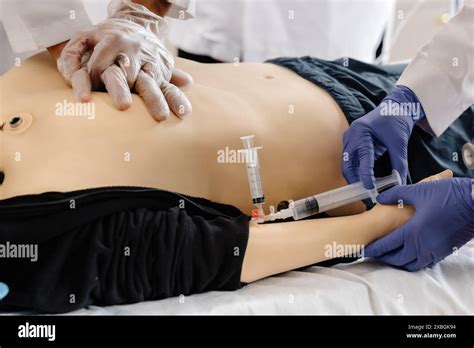 A Medical Babe Practices Intravenous Injection On A Training Dummy During A Practical Skills