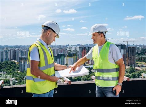 Male Engineers Reading Blueprint Together Stock Photo Alamy