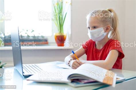 원격 학습 온라인 교육 집에서 공부하고 노트북을 보고 학교 숙제를하는 의료 마스크의 질병 여학생 테이블에 책과 노트북 을 교육