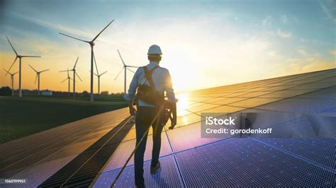 전문 남성 녹색 에너지 엔지니어가 안전 벨트와 안전모를 쓰고 태양 전지판 위를 걷고 있다 풍력 터빈으로 지속 가능한 에너지 농장을 검사하는 남자 Vfx 편집 전기 흐름을