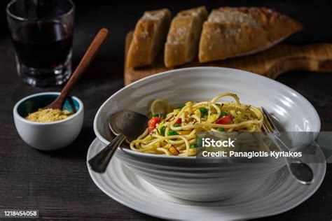 녹색 완두콩 붉은 고추 캐러멜화된 양파 레몬 향을 곁들인 비건 파스타 요리는 화이트 파스타 그릇에 얇게 썬 빵과 레드 와인 한 잔을 얹습니다 0명에 대한 스톡 사진 및 기타