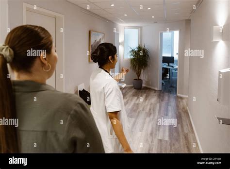 Female Healthcare Worker Escorting Patient Towards Examination Room At