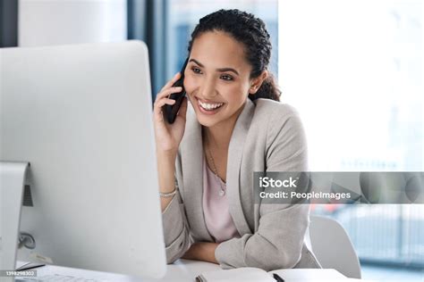 젊은 행복한 혼합 인종 사업가가 전화를 사용하여 전화를 걸고 직장에서 사무실에서 데스크톱 컴퓨터에서 작업합니다 한 히스패닉