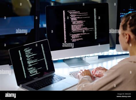 Focus On Computer Screen With Coded Data While It Engineer Sitting By Desk In Front Of Monitor