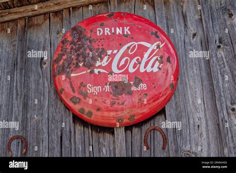 an old vintage porcelain round coca cola sign tattered with some rust