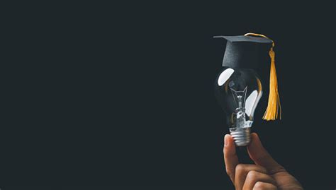 아카데미 및 성공 대학원 교육 개념 사업가는 검은 배경에 학위 캡이 있는 밝은 전구를 들고 있습니다 비즈니스 교육 지식 복사 공간을 통한 학습 아이디어 장학금에 대한 스톡