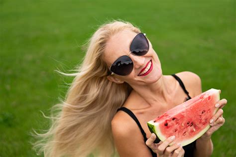 소녀는 광변색 안경을 쓰고 들판을 유혹합니다 아름다운 숲 뒤에서 검은 모자를 쓴 수박의 식욕을 돋우는 조각 기록보관용에 대한 스톡 사진 및 기타 이미지 Istock