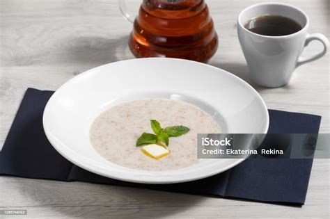 버터와 민트 잎이 달린 흰색 접시에 우유 죽을 차 한 잔과 함께 나무 배경에 놓습니다 건강한 아침 식사 적절한 아침 0명에 대한 스톡 사진 및 기타 이미지 Istock