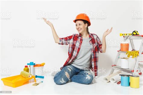 재건축 아파트 룸 흰색 배경에 고립에 대 한 악기와 함께 바닥에 앉아 오렌지 보호 헬멧에 여자 배경 화면 접착 페인팅 도구에 대 한 액세서리입니다 수리 가정 개념입니다