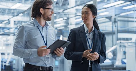 두 명의 다양한 엔지니어가 사무실에서 태블릿 컴퓨터를 사용하여 현대 전자 공장에서 걷고 있습니다 여성과 남성 전문가들이 현대