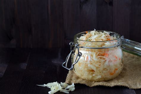 검은 색 배경에 유리 항아리에 허브와 당근과 수제 소금에 절인 양배추 나무 테이블에 자루가 있는 양배추절임 복사 공간을 복사합니다 통조림 식품의 개념 채식 음식 0명에 대한