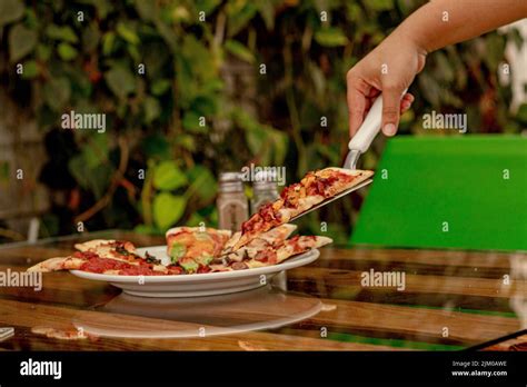 A Closeup Of The Hand Taking A Slice Of Pizza By A Pizza Server Stock