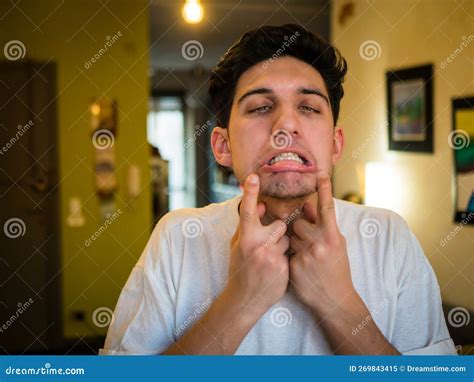 Young Man Pulling Corners Of Lips Down Making Unhappy Facial Expression