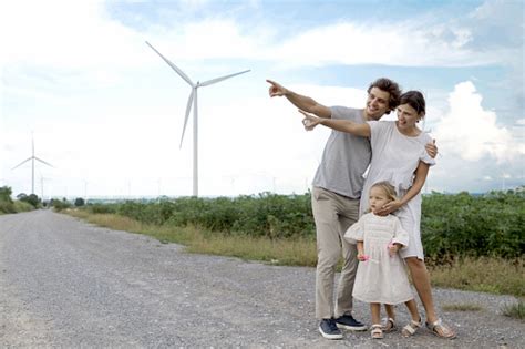 풍력 터빈 농장의 행복한 가족 흐린 하늘을 배경으로 풍차공원에서 아빠와 엄마 딸이 함께 시간을 보낸다 가리키는 부모와 함께 어린 소녀 아이 생태학 대체 재생 가능 에너지 3