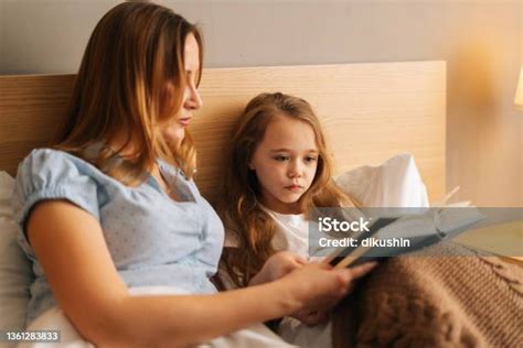 젊은 행복한 어머니와 사랑스러운 쾌활한 딸의 옆면 보기는 잠들기 전에 함께 침대에 누워 있는 아이들을 읽는 다 아이에 대한 스톡 사진 및 기타 이미지 Istock