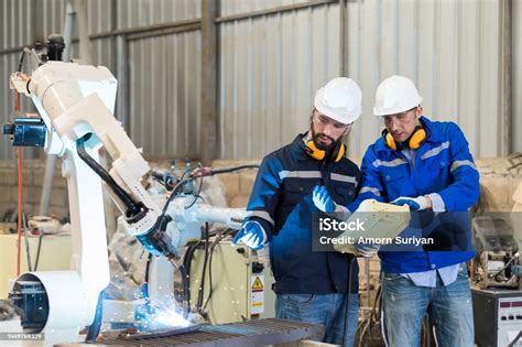 두 명의 남성 엔지니어가 생산 라인 공장 공장에서 로봇 암 용접을 논의하고 제어합니다 스마트 팩토리 산업에서 자동 로봇 암 시스템 용접기를 작업하는 엔지니어 작업자 20
