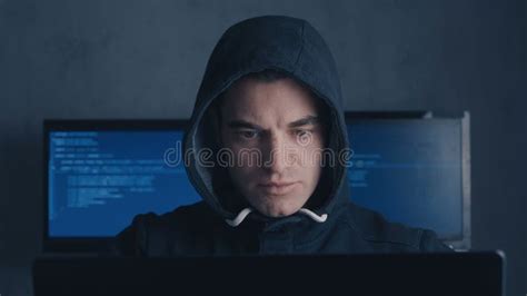 wanted man hacker in hood working on a computer in data center stock