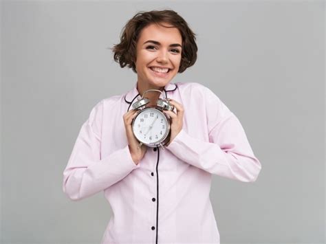 Улыбающаяся девушка в розовой рубашке с будильником в руках обои для рабочего стола картинки