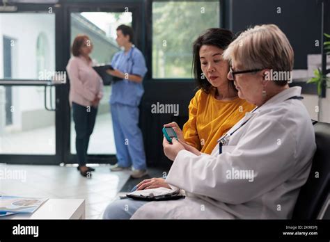 Senior Physician Consulting Asian Patient With Glucometer Measuring Insulin And Glucose Level