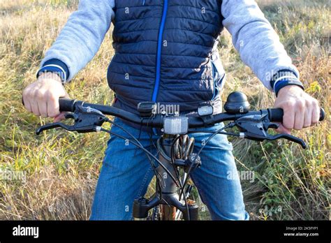 Person Riding A Bike A Man Holds The Handlebars Of A Bicycle On Grass Background On A Field
