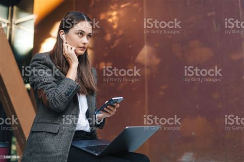 노트북을 사용하여 사무실 건물 앞 계단 위에 앉아 전화기를 들고 있는 젊은 여성의 초상화 야외에서 개인용 컴퓨터를 사용하는 사람 매력적인 아름다운 소녀 25 29세에 대한