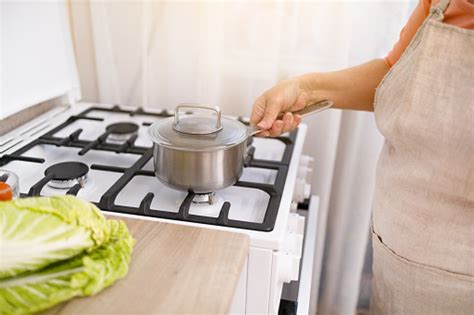 여자는 현대 부엌에서 가스 난로에 스테인레스 요리 냄비를 넣습니다 음식을 준비하기위한 재료 수제 식품 컨셉 강철에 대한 스톡