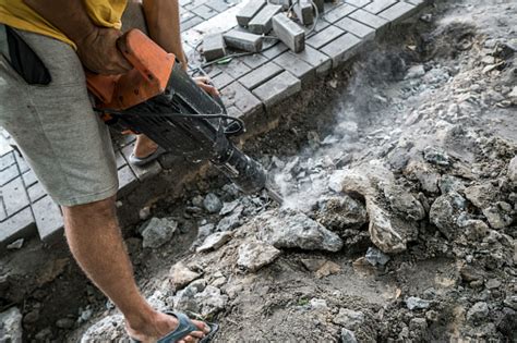 노동자는 전기 콘크리트 브 레이 커를 사용합니다 남성 노동자 수리 차도 표면 착 암기 파고 및 보도 건축 도중 콘크리트도 시추 작동 합니다 건설 기계류에 대한 스톡 사진 및