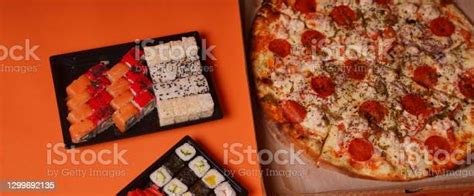 용기에 식욕을 돋우는 초밥과 오렌지 배경상자에 큰 피자를 닫습니다 피자와 다른 재료와 맛있는 초밥 롤 세트 0명에 대한 스톡