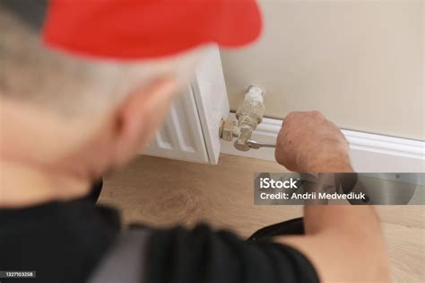 방에 난방 라디에이터를 설치하는 동안 렌치를 사용하여 작업 바지에 남자 아파트에 난방 시스템을 설치 배관공 라디에이터 설치 배관 작업 및 주택 개조의 개념 55 59세에