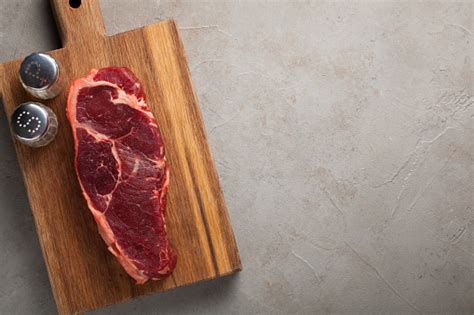 원시 쇠고기 차 돌 박이 빈티지와 스테이크 칼 오래 된 돌 배경에 백색 후추와 소금 나무 보드에 고기 조각 뉴욕 스테이크입니다 복사 공간 평면도 갈비 음식에 대한 스톡 사진